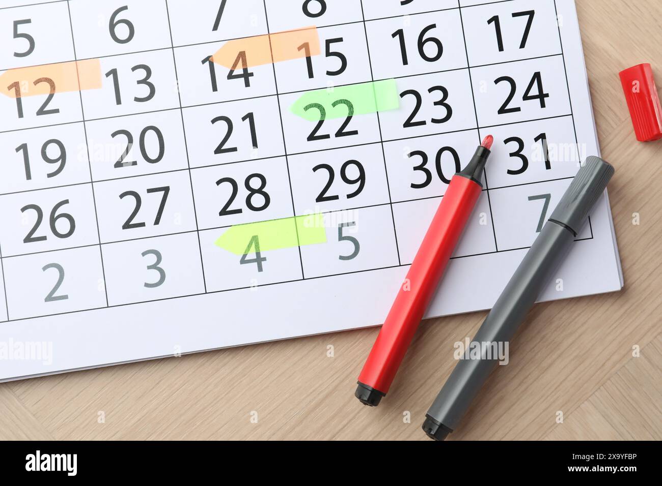 Timetable. Calendar page with marked dates and felt pens on wooden ...
