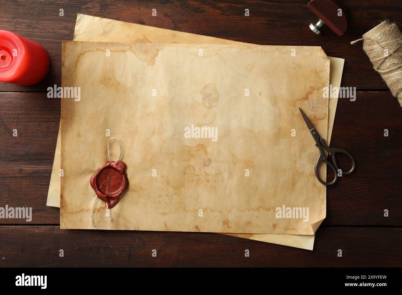 Sheet of old parchment paper with wax stamp, rope, scissors and candle ...