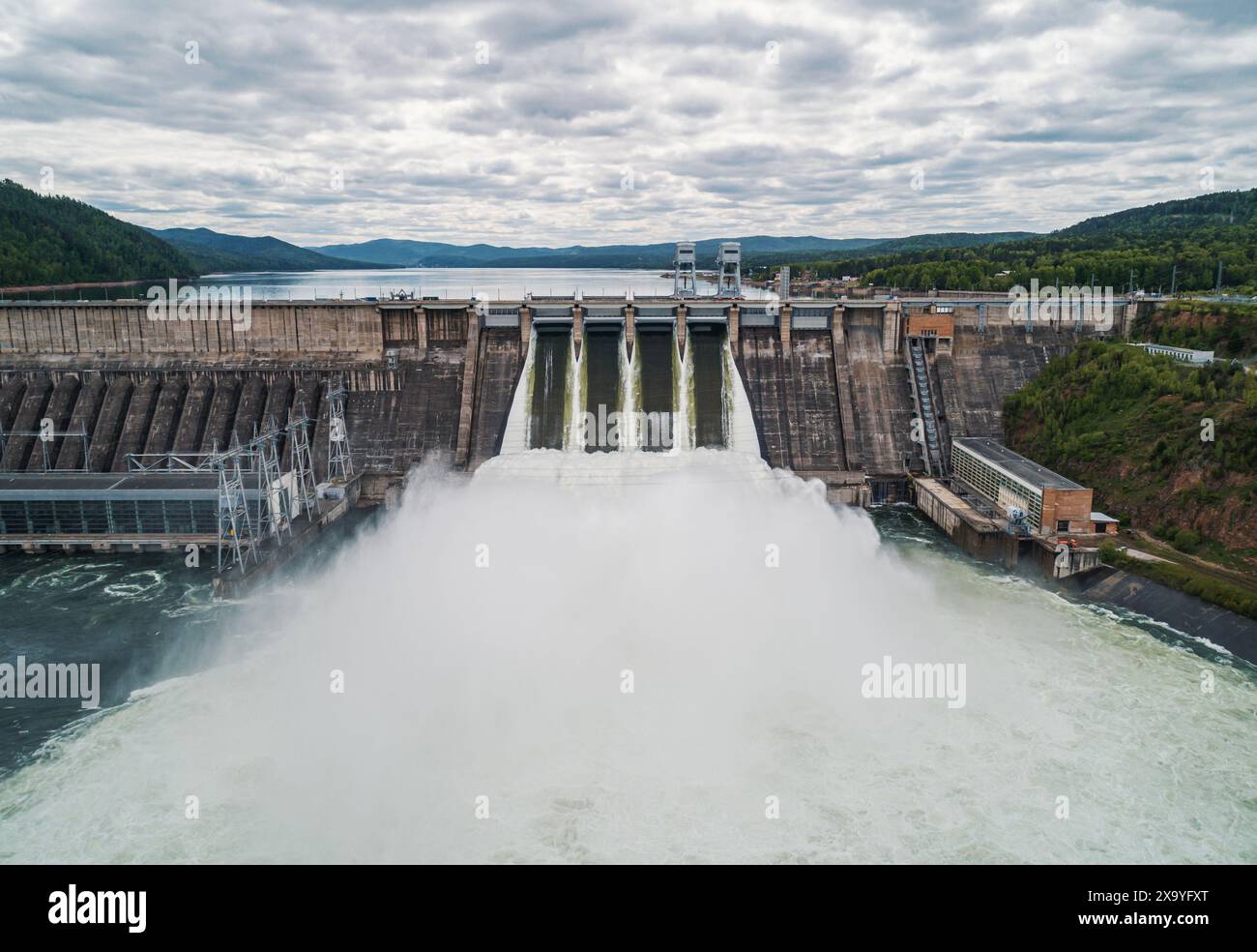 Aerial view of concrete dam releasing water into river on cloudy day ...