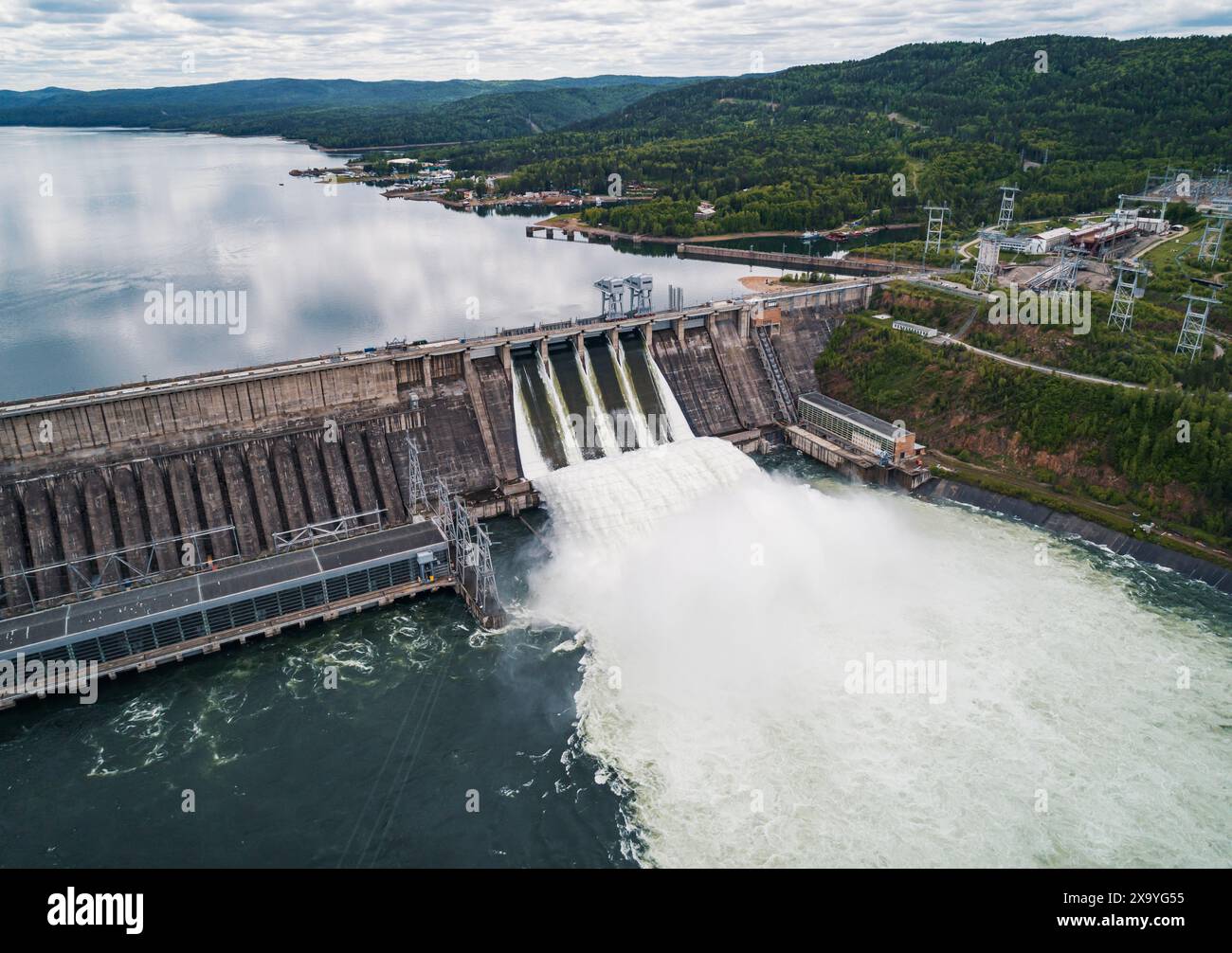 Aerial view of concrete dam releasing water into river on cloudy day ...