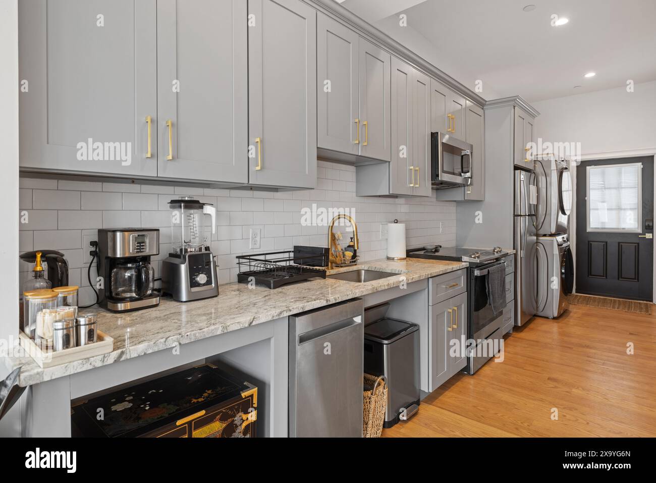 A Modern grey kitchen cabinets with elegant gold hardware on doors and ...