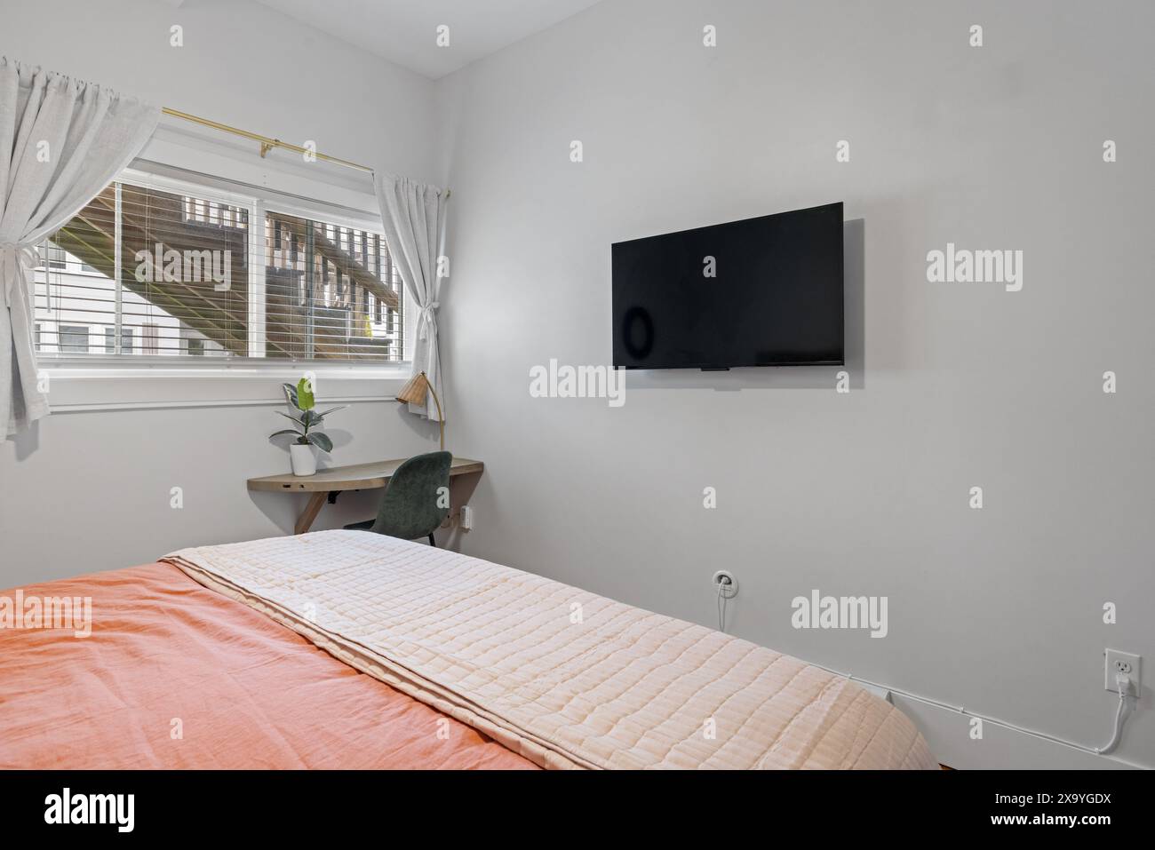 A bedroom featuring a wall-mounted flat screen TV above a cozy bed ...