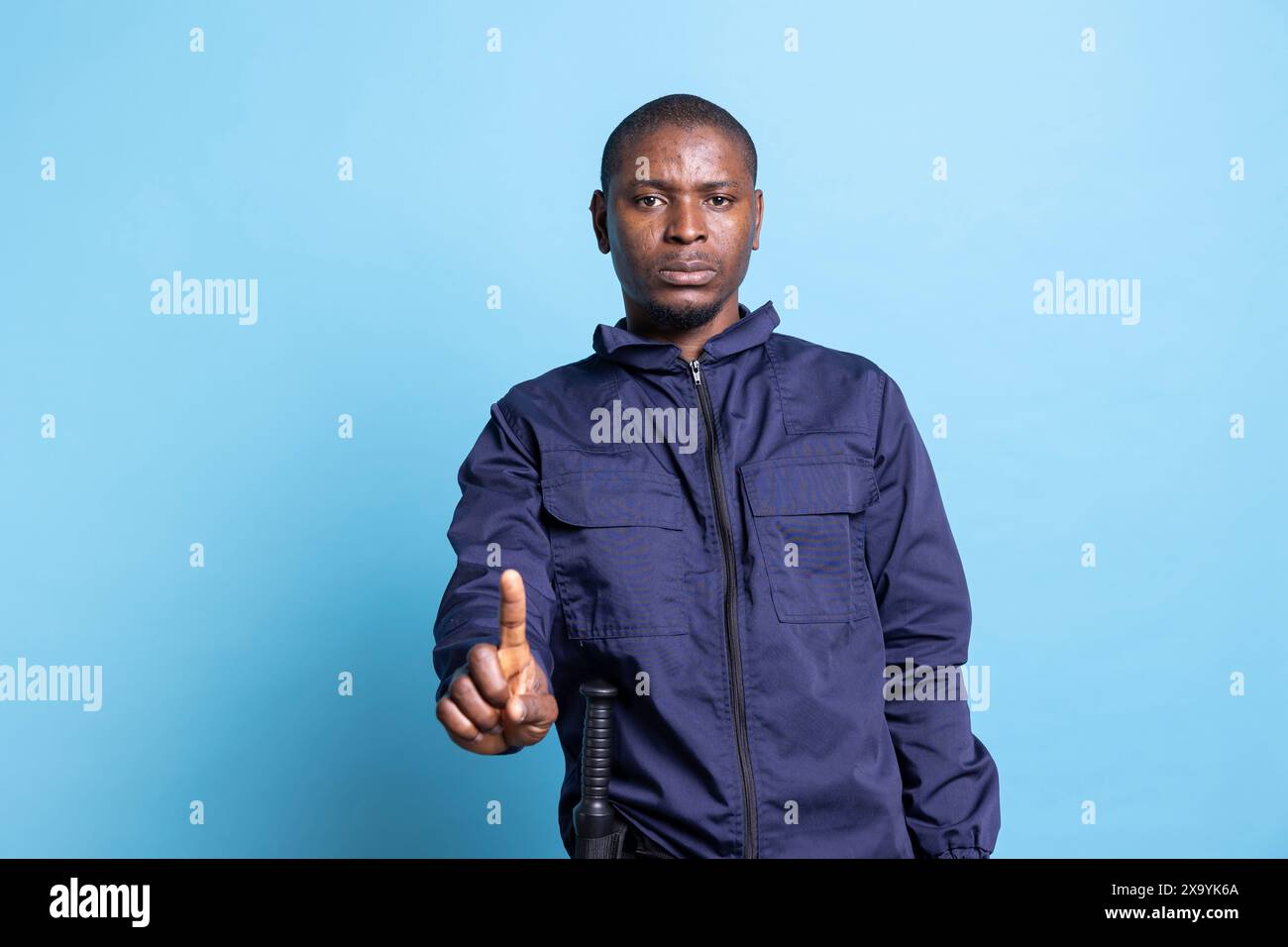 African american security guard poses with a finger up in studio ...
