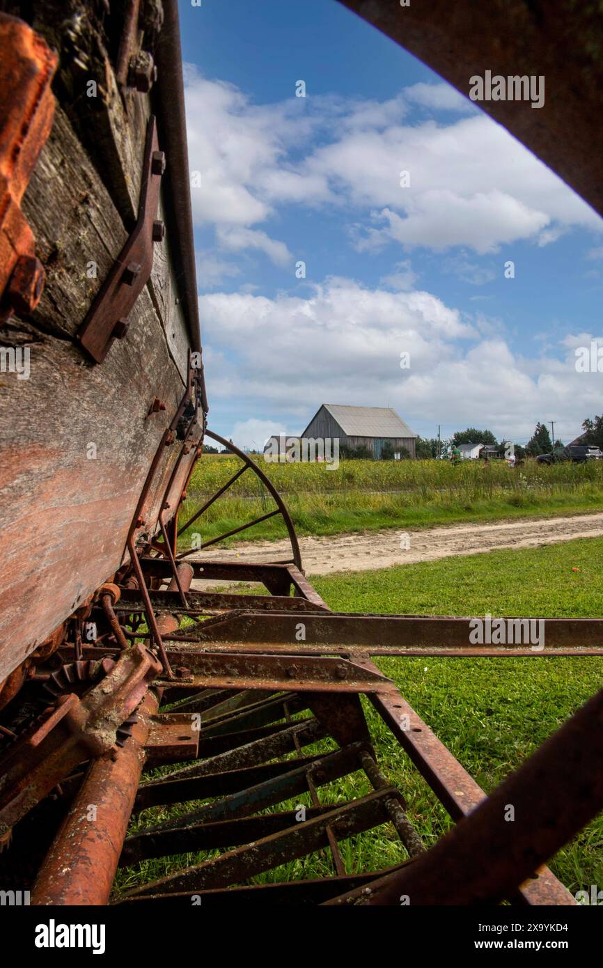 Rusty horse-drawn carriage in field with barn in background Stock Photo ...