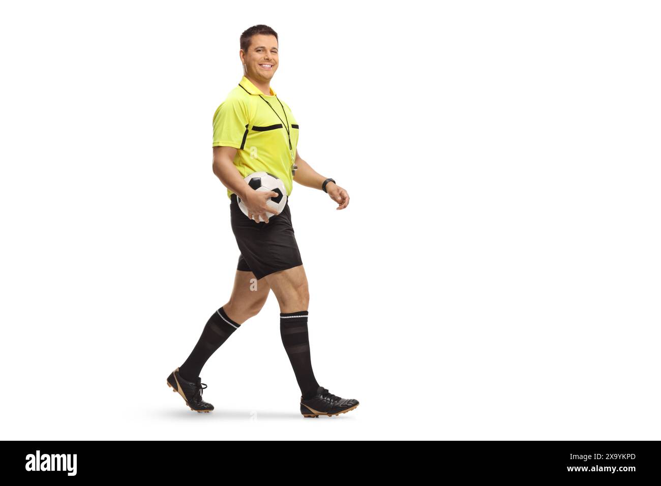 Full length shot of a football referee walking and holding a ball ...