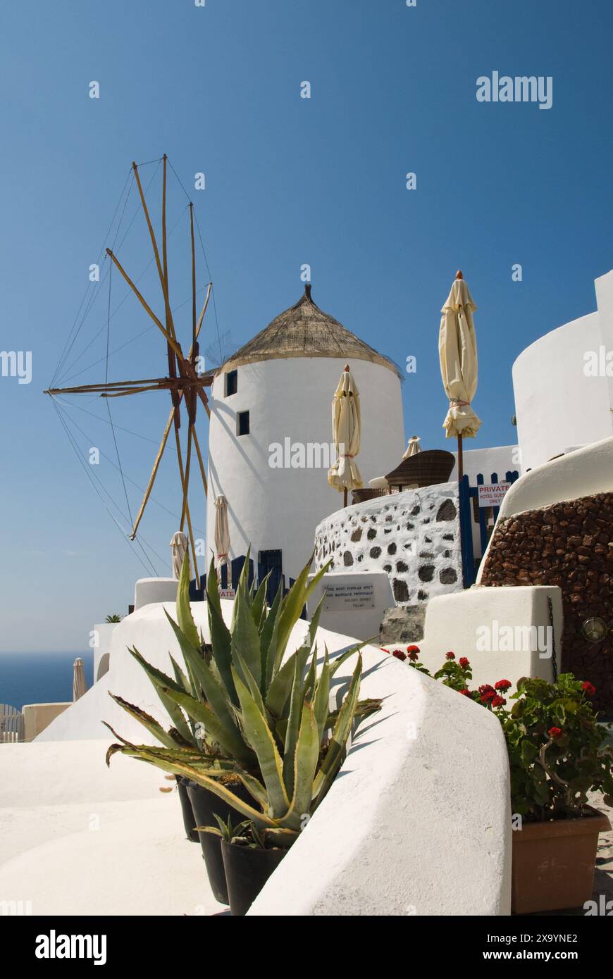 A bright white windmill in sunlight on a clear day in Oia, Greece Stock ...