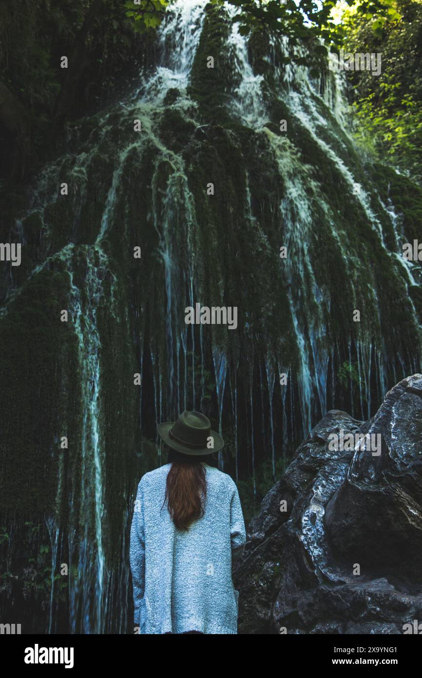 A vertical shot of a woman standing by a waterfall in Kabood Vall ...