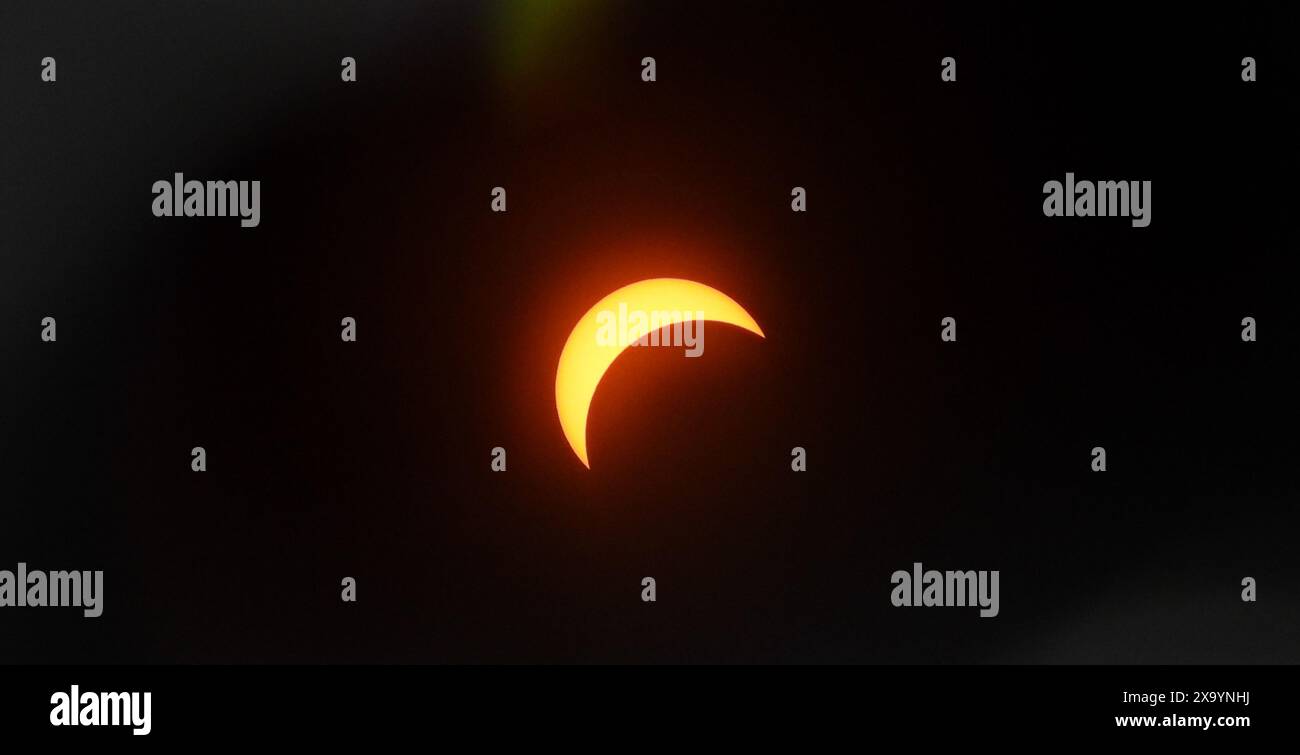 The solar eclipse with a glowing crescent in the dark sky Stock Photo ...