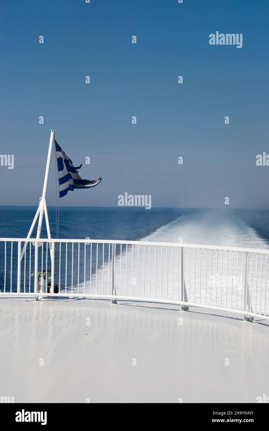 A boat sailing off with a flag flying in the wind in Kykladen, Greece ...