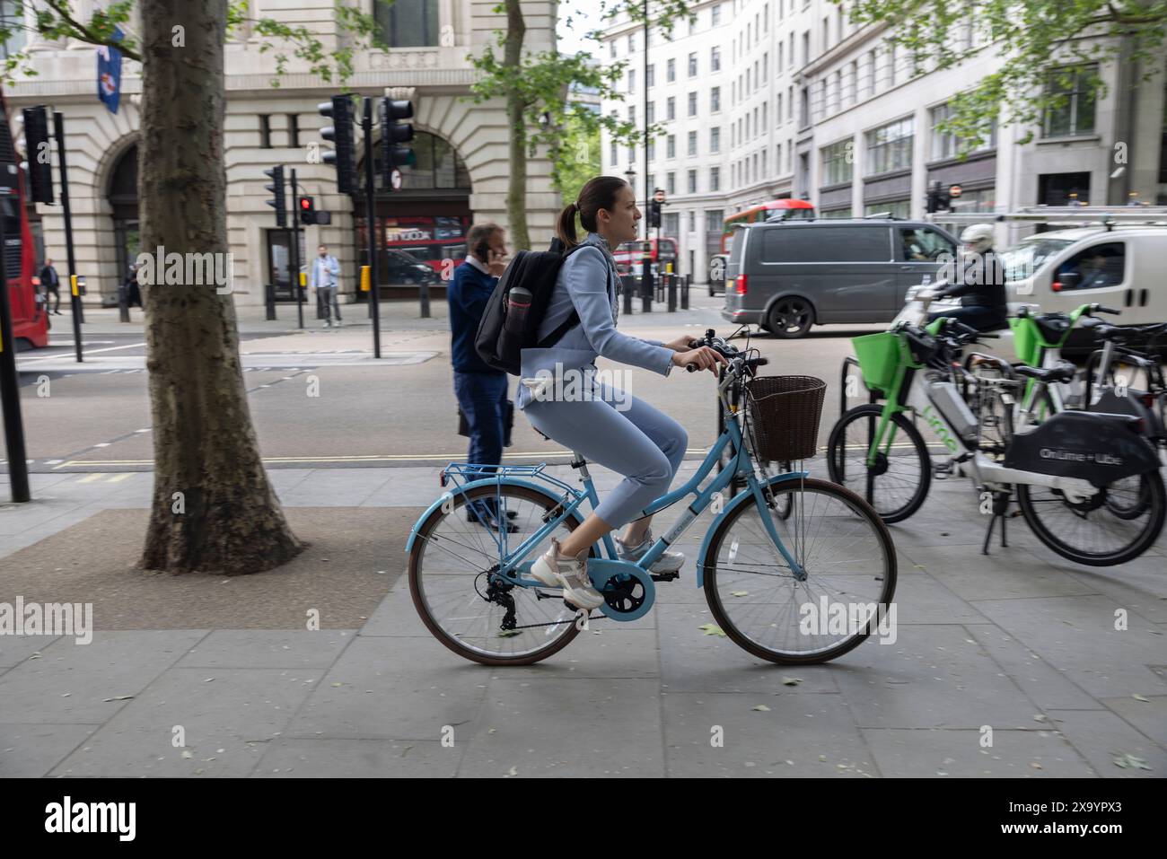Young woman cycling to work along the pedestrian pavement in Aldwych ...