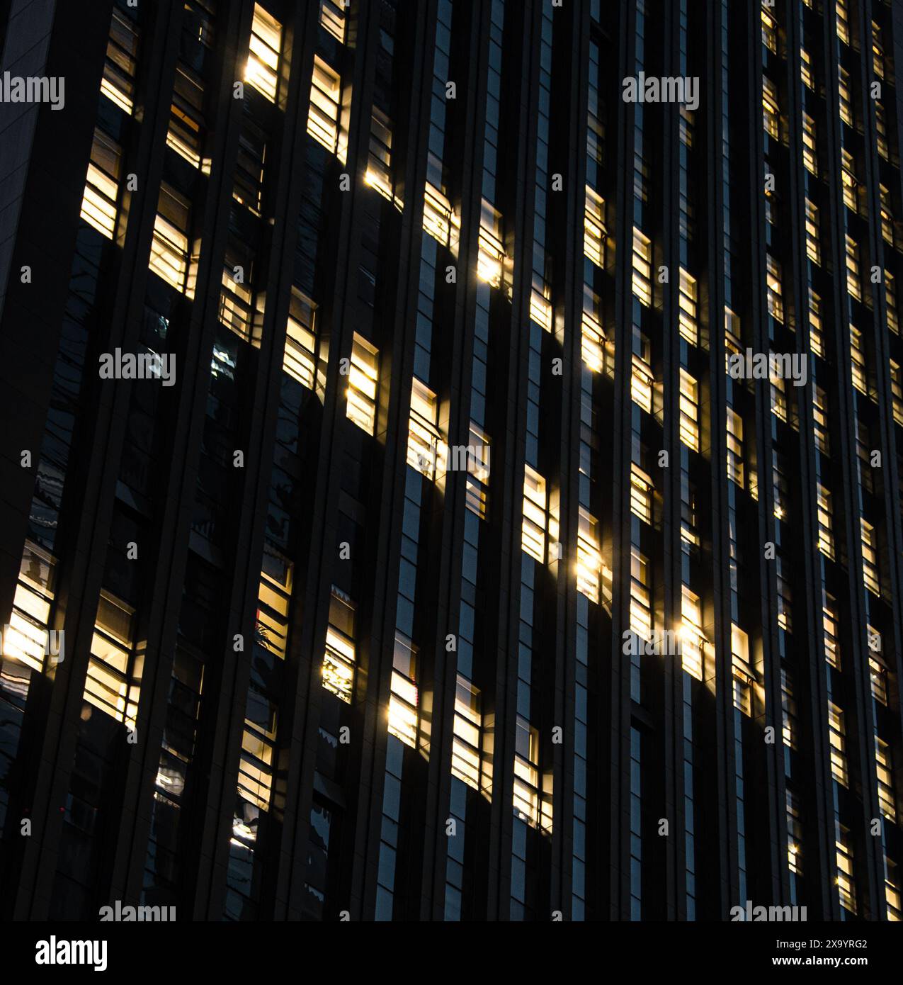 A skyscraper decorated with glass curtain walls in the dark, some rooms ...