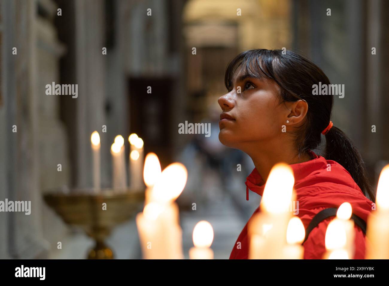 Teenage girl in a red jacket praying in a church by candlelight Stock ...