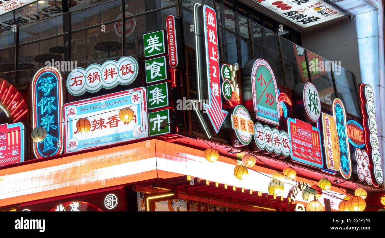 A bustling street scene at night with illuminated signs. Wuhan, China ...