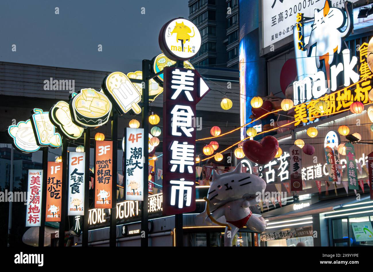 A bustling street scene at night with illuminated signs. Wuhan, China ...