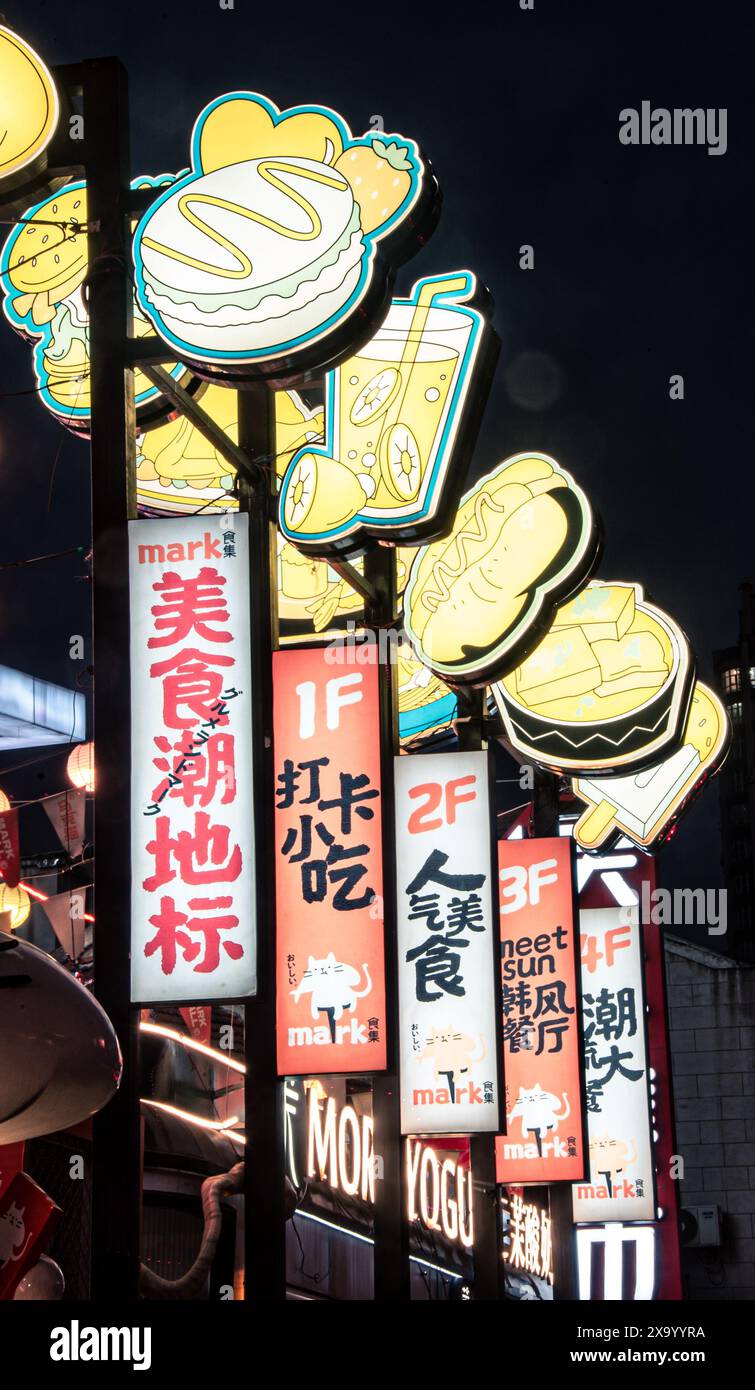 A bustling street scene at night with illuminated signs. Wuhan, China ...