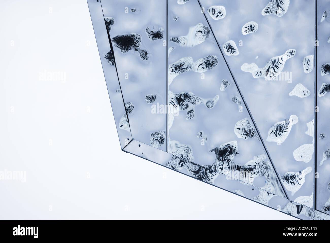 Shiny steel corner of modern facade is under bright sky, blue toned ...