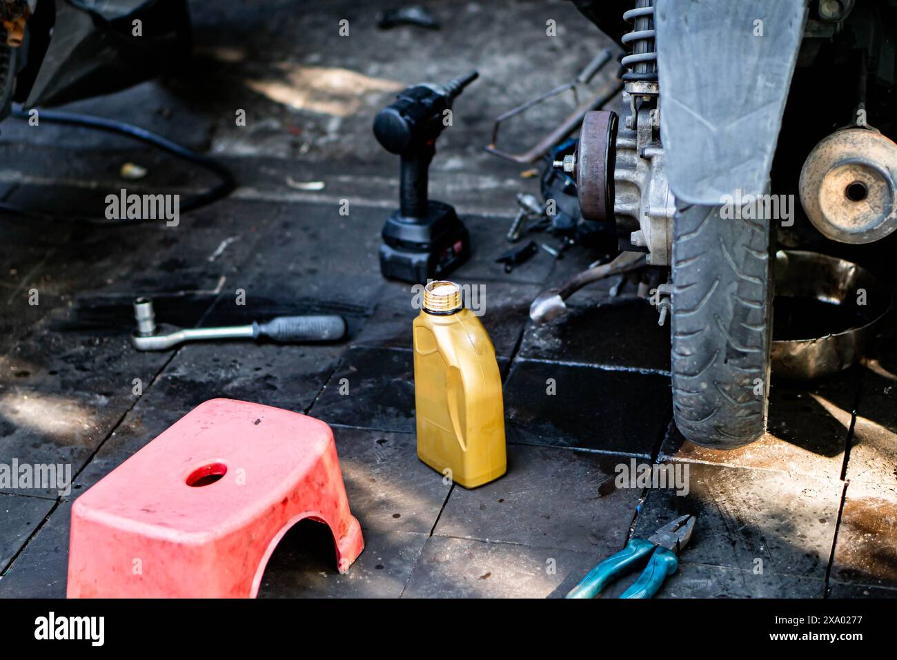 A car repair scene with tools and a bottle of motor oil on the ground ...