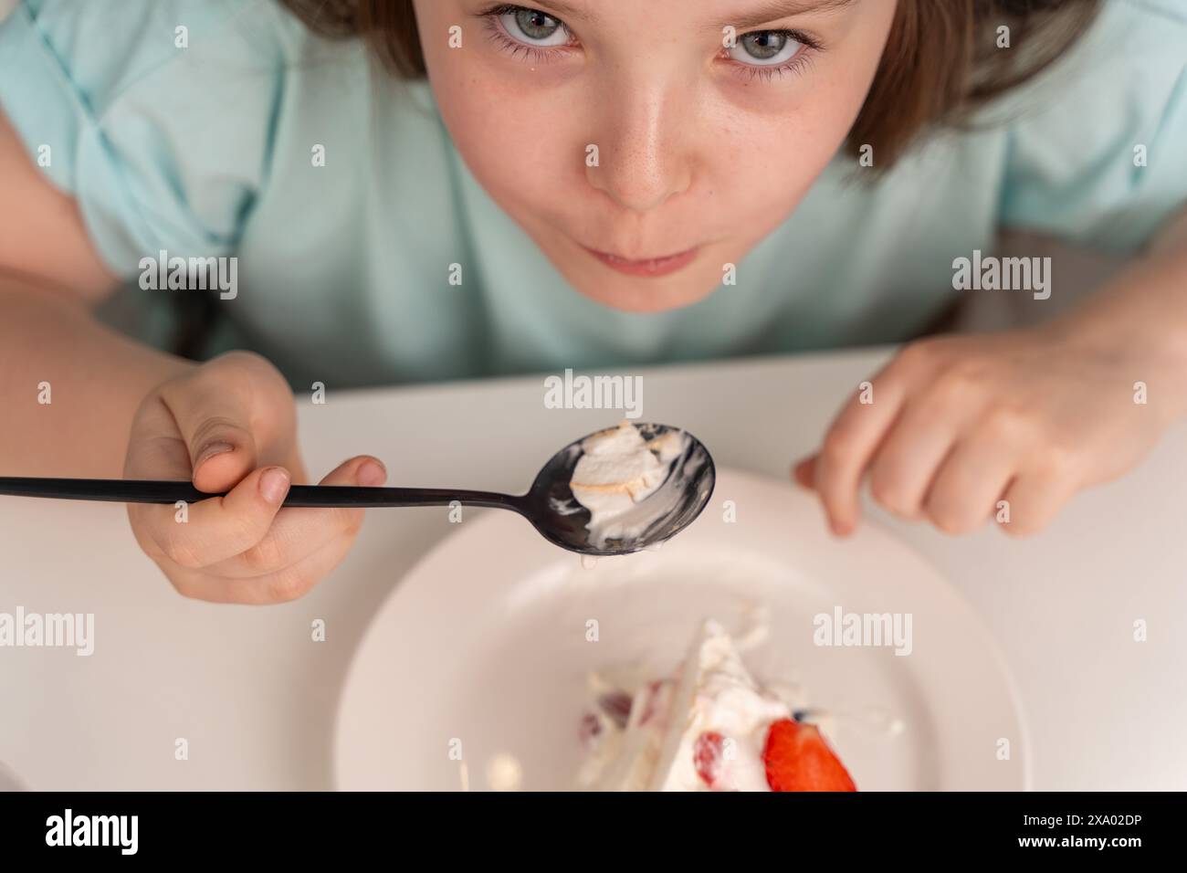 Cute little girl eating delicious cake with a big spoon. Close-up ...