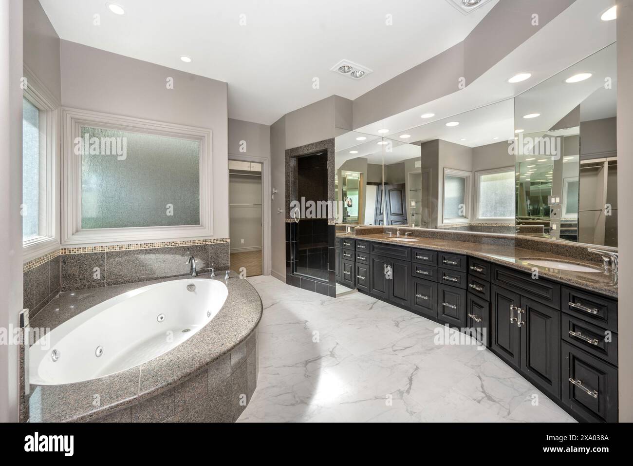 A spacious white and gray bathroom with jacuzzi tub by windows in ...