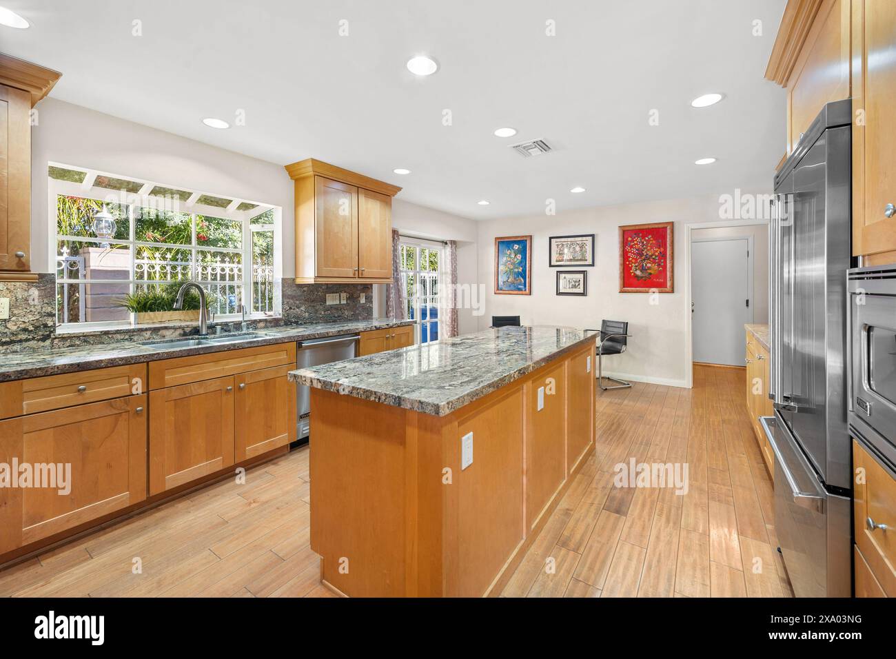 A spacious kitchen with granite counters and wooden cabinets in Encino ...