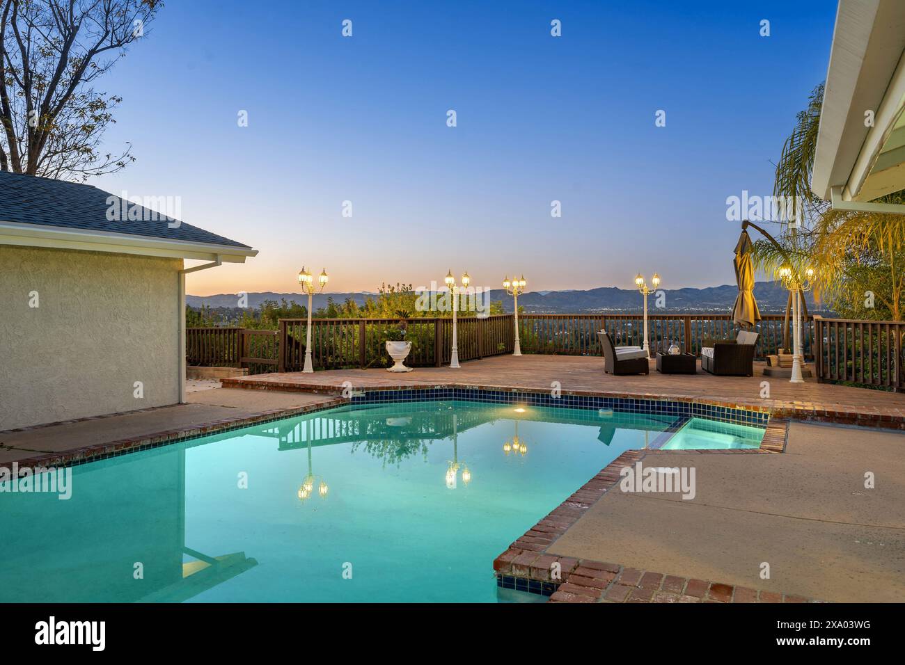 An outdoor pool at sunset with illuminated patio furniture and lights ...