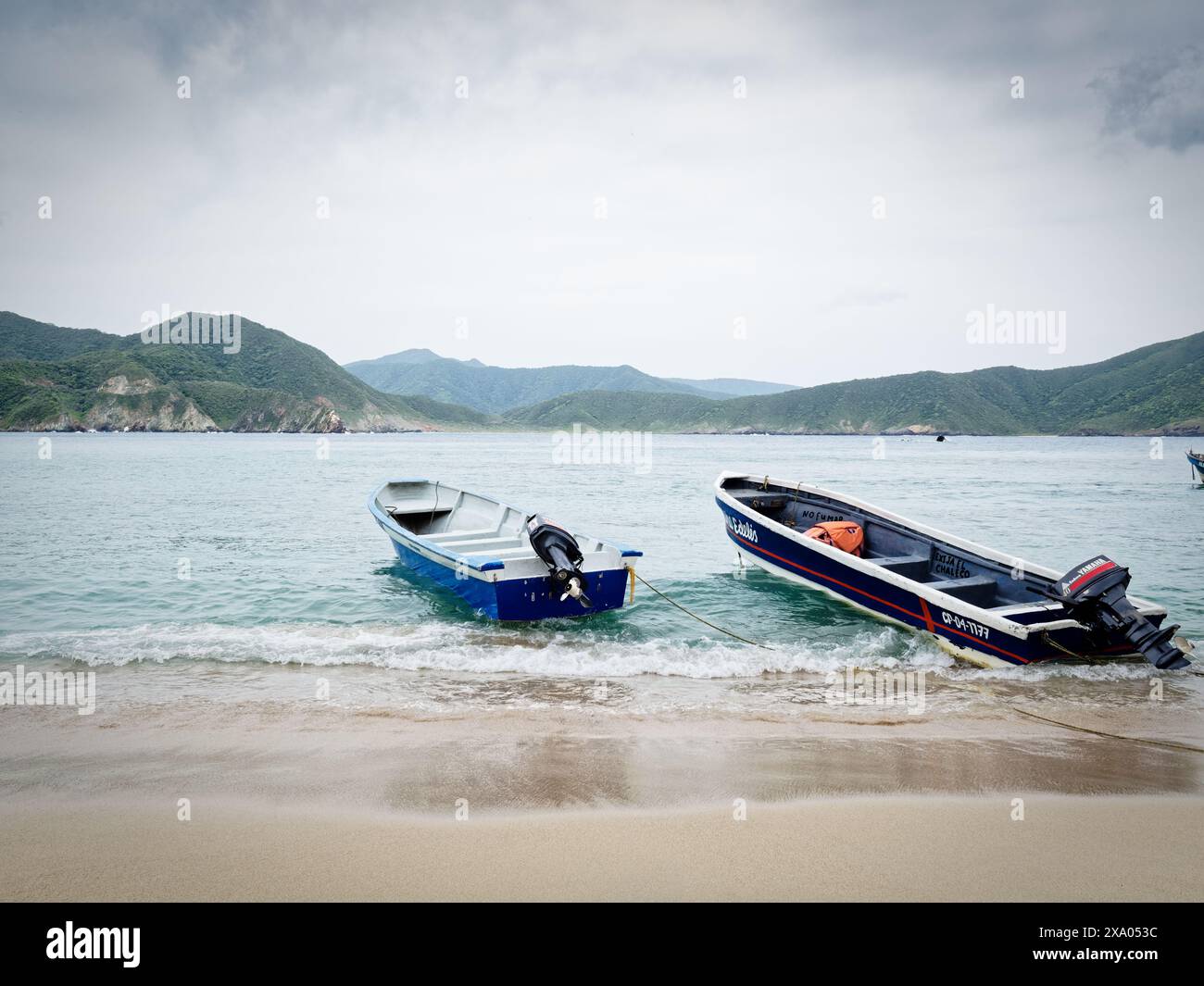 Two small boats on beach with mountains in background Stock Photo - Alamy