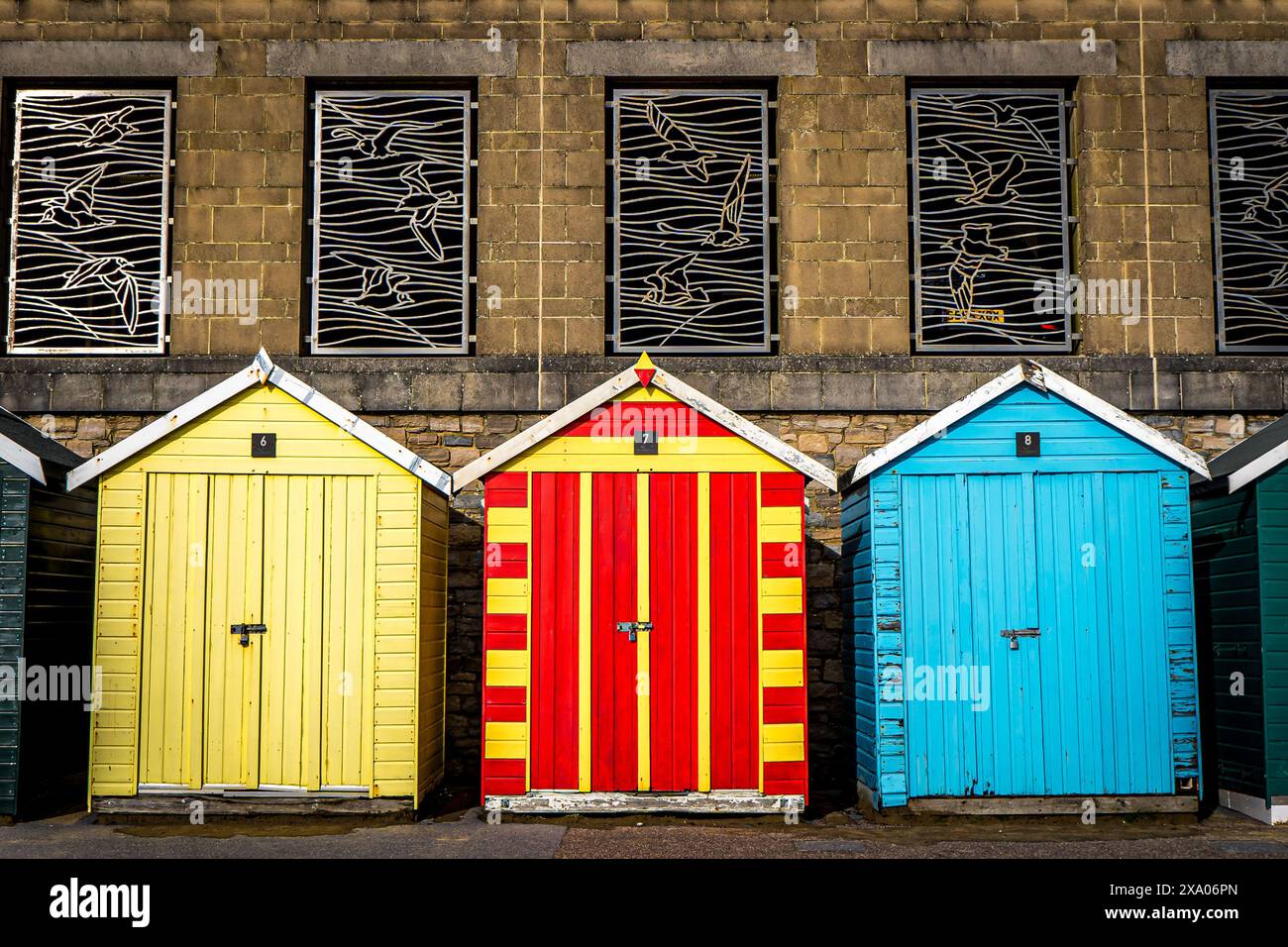 A row of colorful beach huts lined up by a brick wall Stock Photo - Alamy