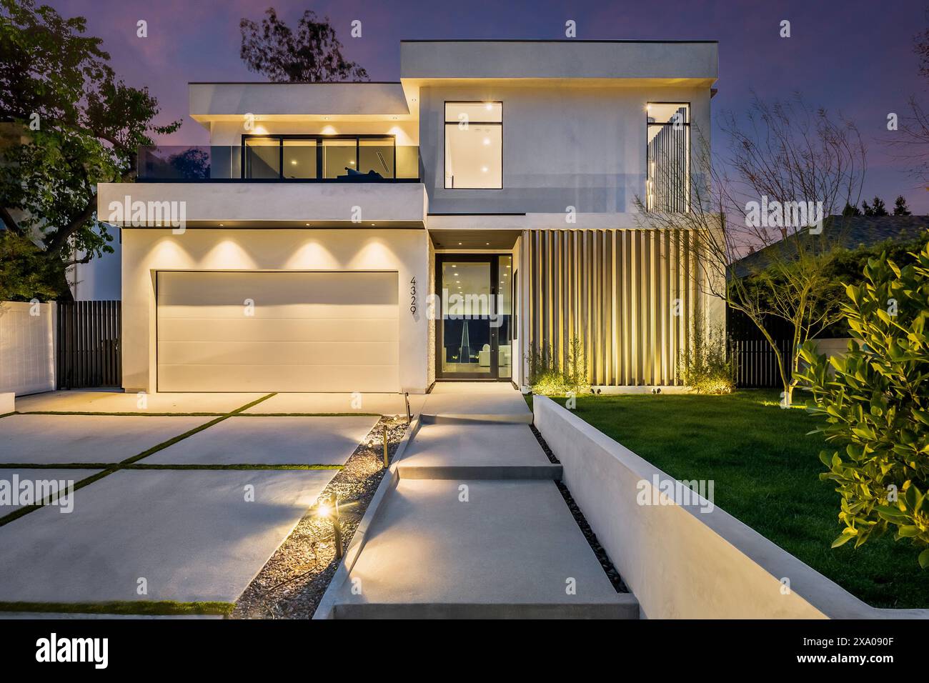Illuminated modern home exterior with concrete driveway and lawn at ...