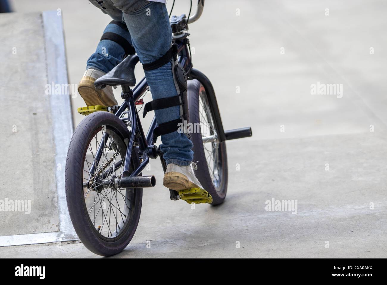 Child on bicycle descends ramp during daytime, holding helmet Stock ...
