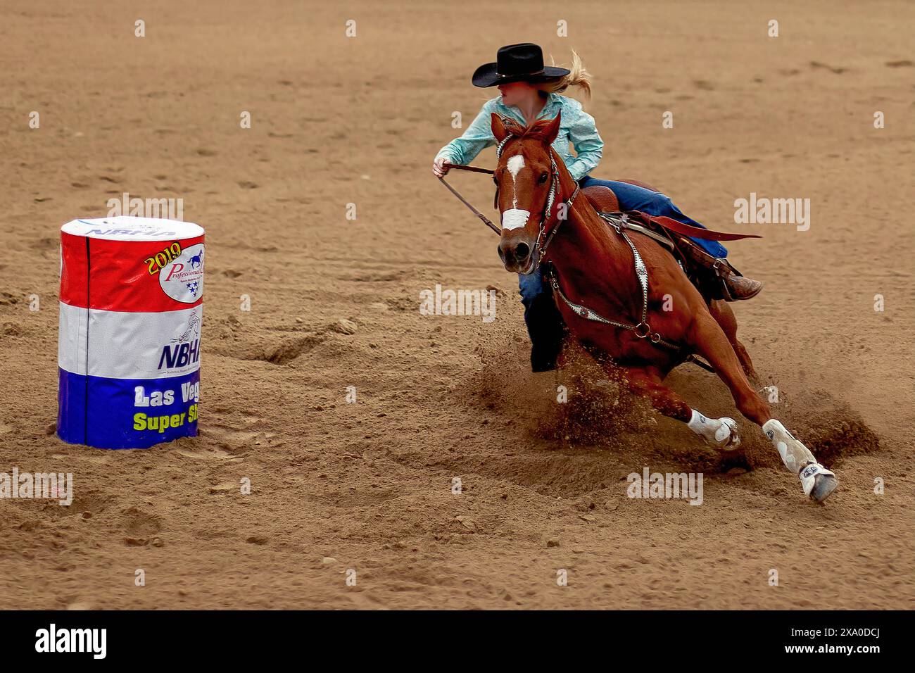 A female equestrian navigating obstacle barrels on horseback Stock ...