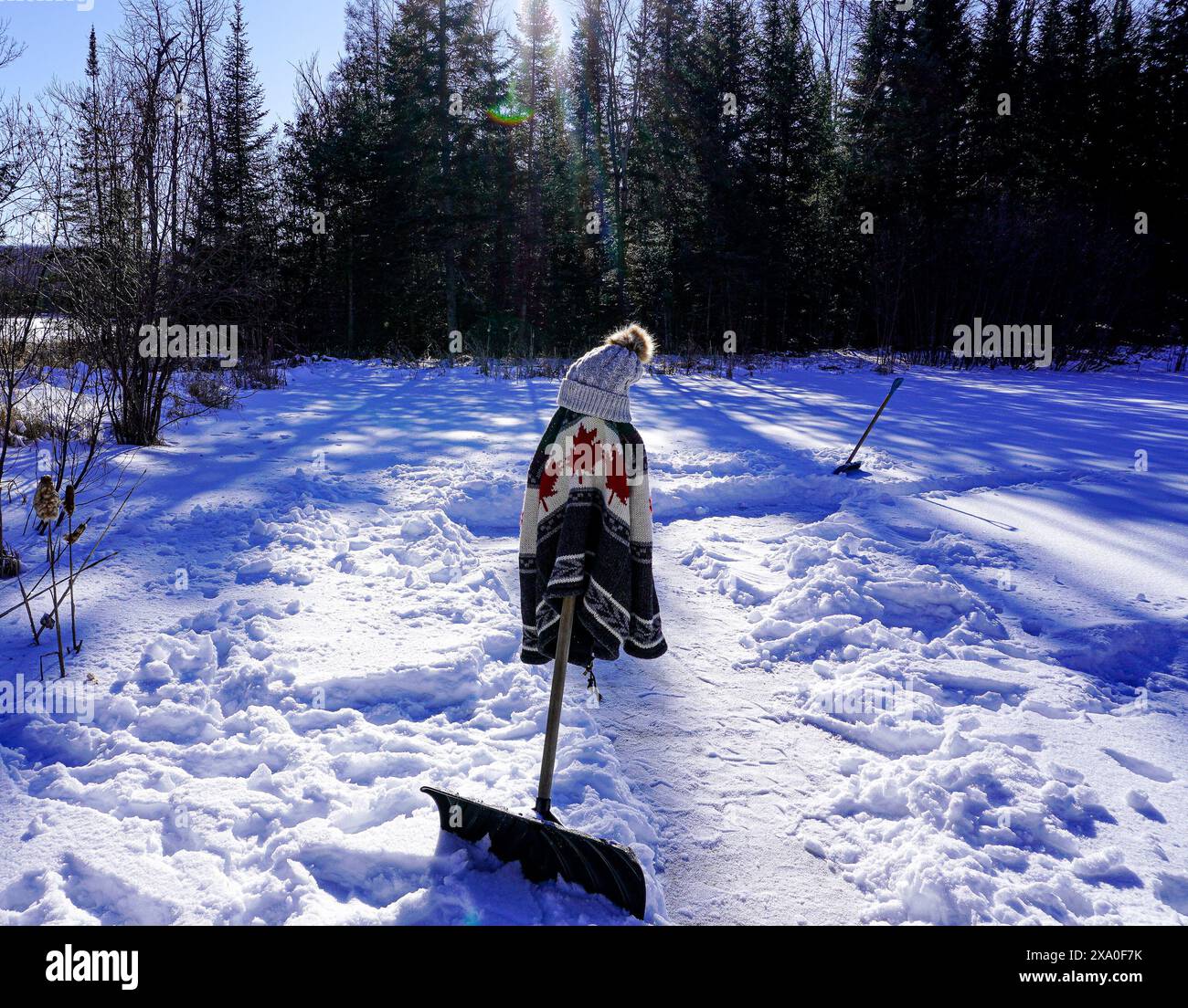 A Canadian flag-themed coat and hat on a shovel, ready for ice rink ...