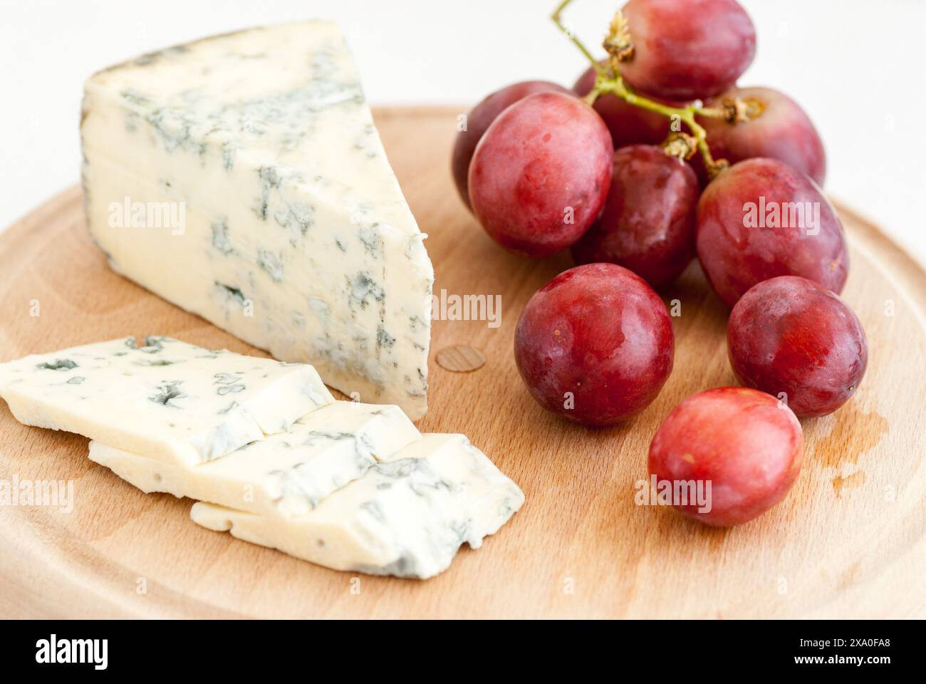 tasty sliced moldy cheese and red grapes on wooden plate Stock Photo ...