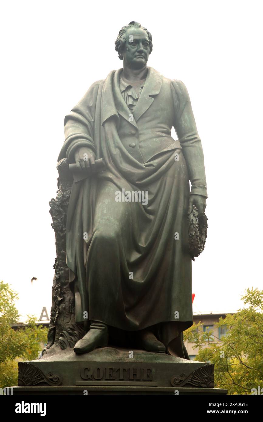 A bronze statue of a figure perched atop a cylindrical green stone ...