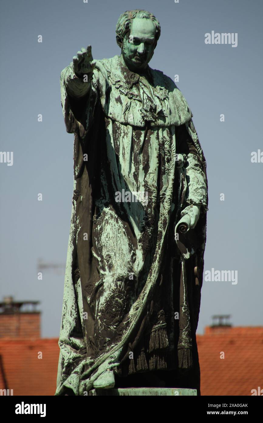 A bronze statue of a seated figure with their arm outstretched, resting ...