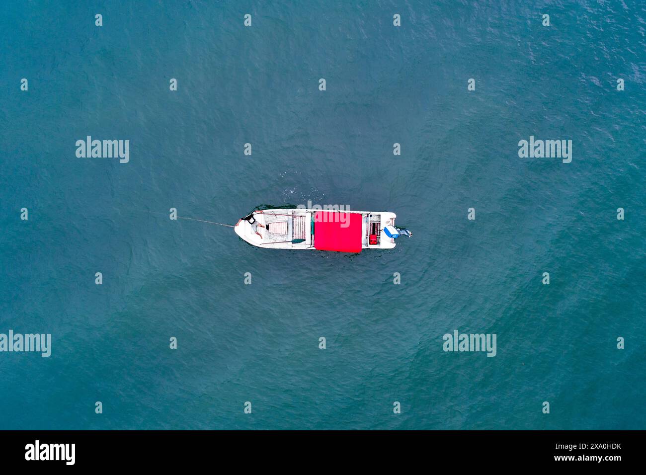 A top-down view of a small fishing boat with a bright red canopy on a ...