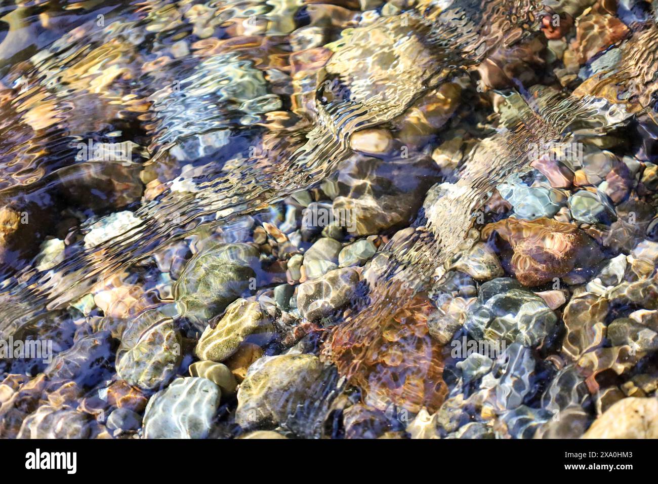 Crystal clear water cascading over smooth rocks in a shallow stream ...