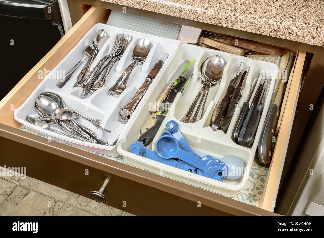 Horizontal shot of a messy and cluttered silverware drawer in the home ...