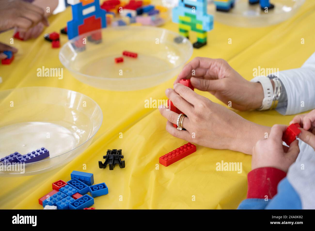 Female hands of a mother helping her child putting together the ...