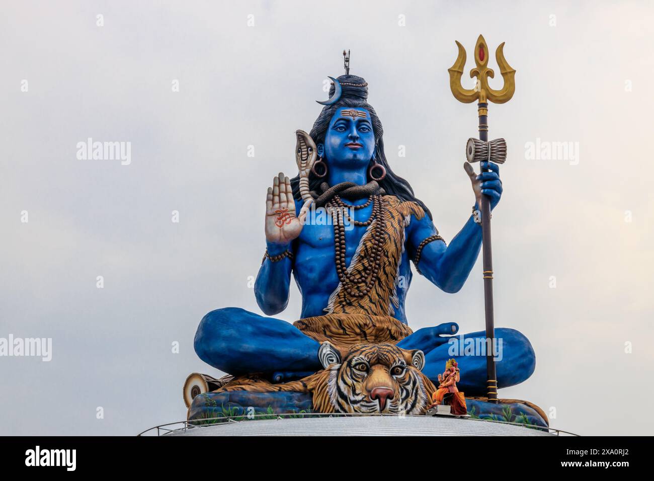Blue statue of Lord Shiva seated with a tiger skin, holding a trident ...