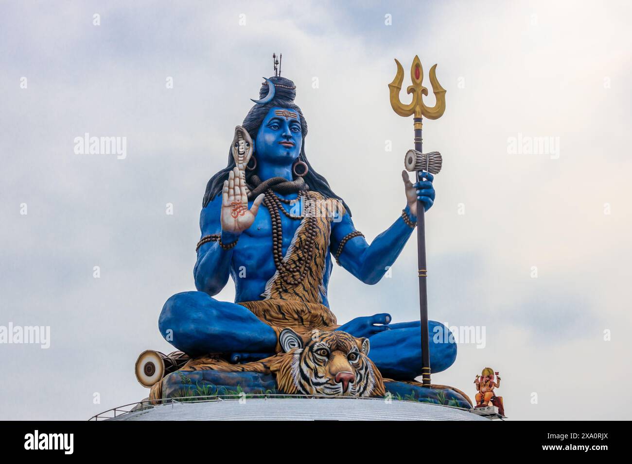 Blue statue of Lord Shiva seated with a tiger skin, holding a trident ...