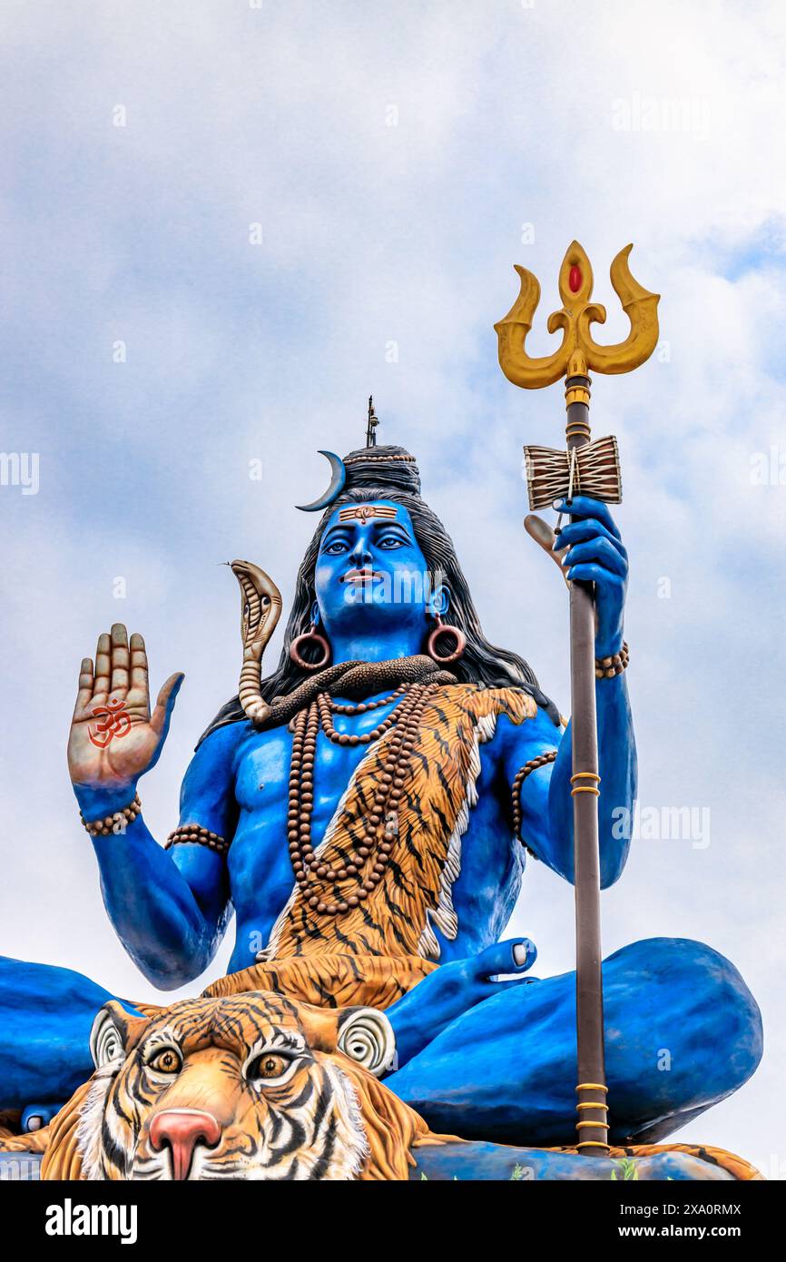 Blue statue of Lord Shiva seated with a tiger skin, holding a trident ...