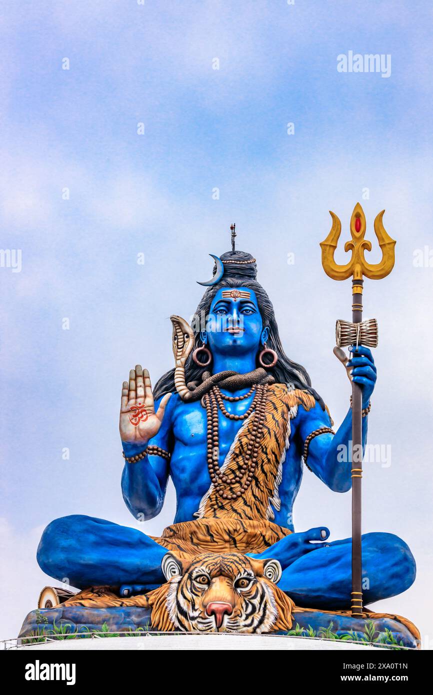 Blue statue of Lord Shiva seated with a tiger skin, holding a trident ...