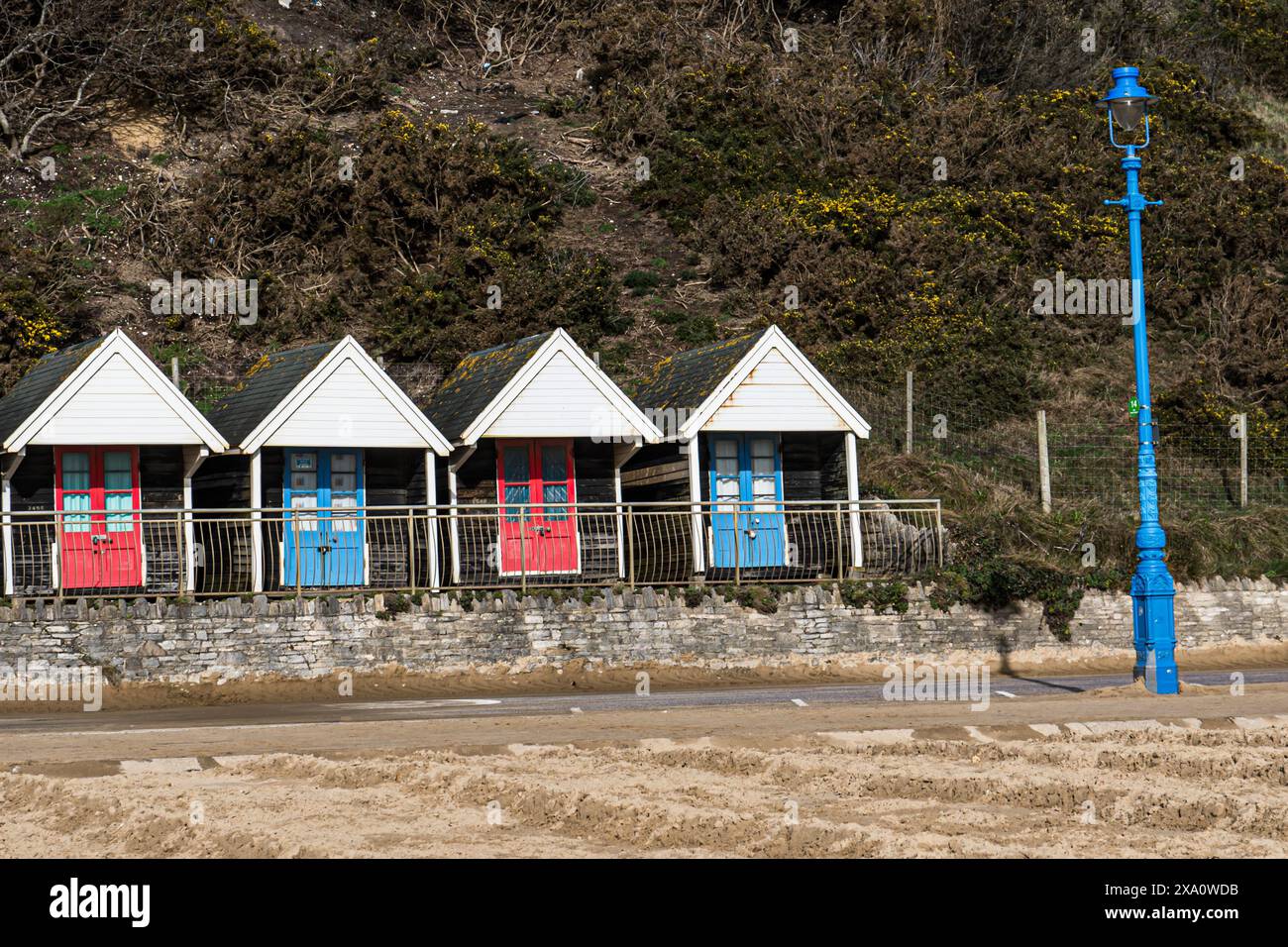 The red and blue beach huts in a row with a blue lamp post at the beach ...