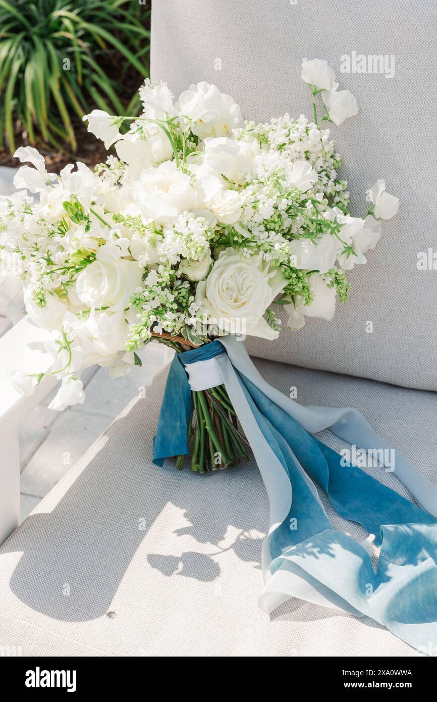 A chair decorated with a bouquet of flowers tied with a blue ribbon ...