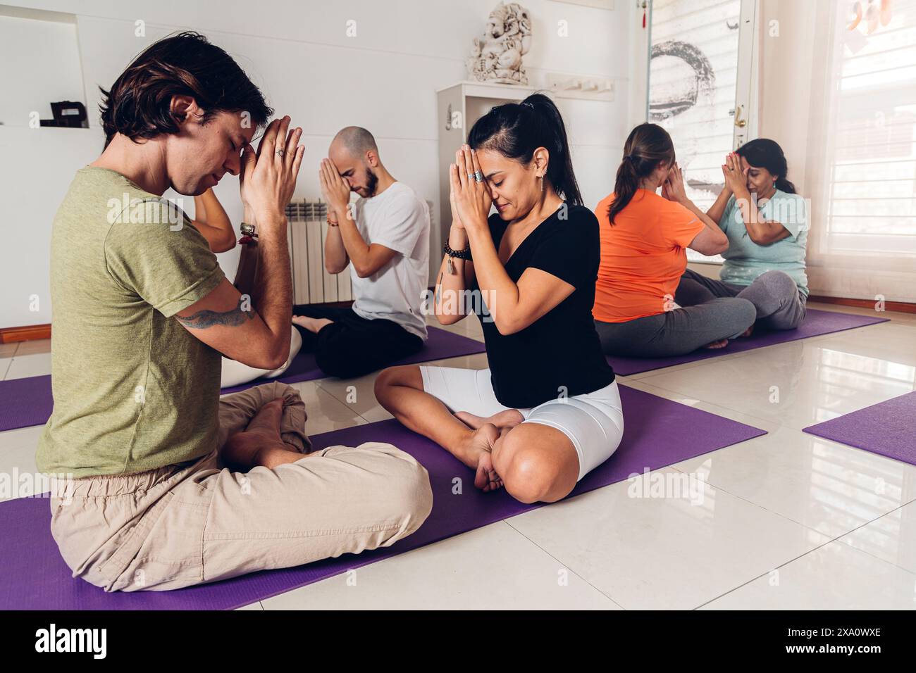 People in a yoga class. They do the prayer position with their hands ...