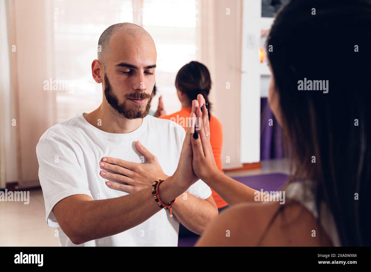 Young couple touching hands while practicing yoga posture together in ...