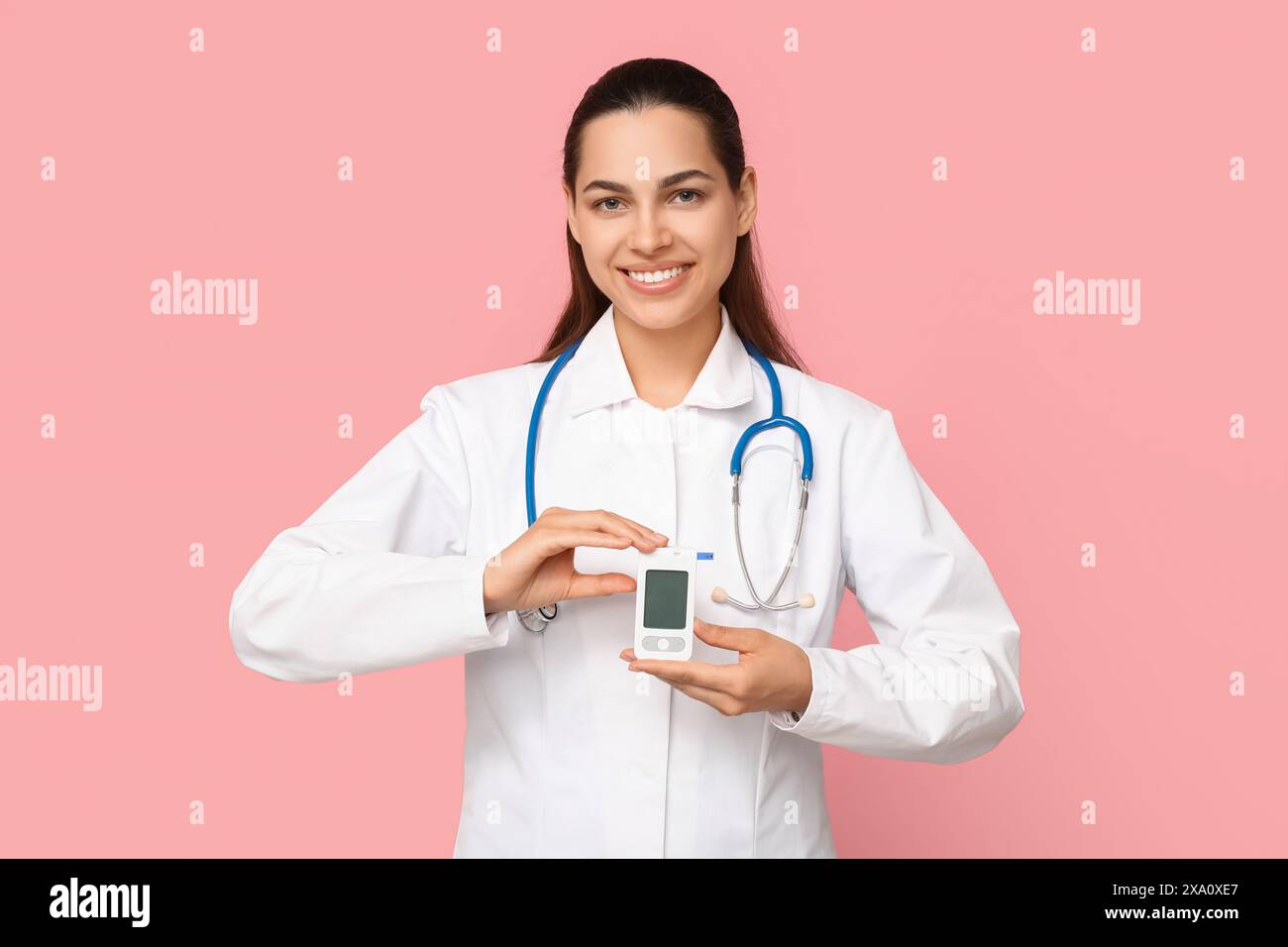 Portrait of female doctor with portable glucose meter on pink ...