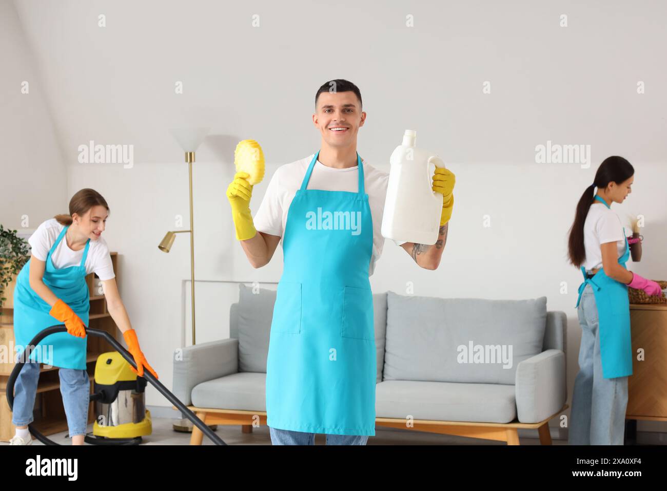 Male janitor with cleaning sponge and detergent in room Stock Photo - Alamy