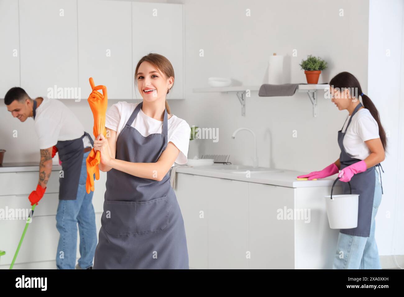 Female janitor putting on rubber gloves in kitchen Stock Photo - Alamy