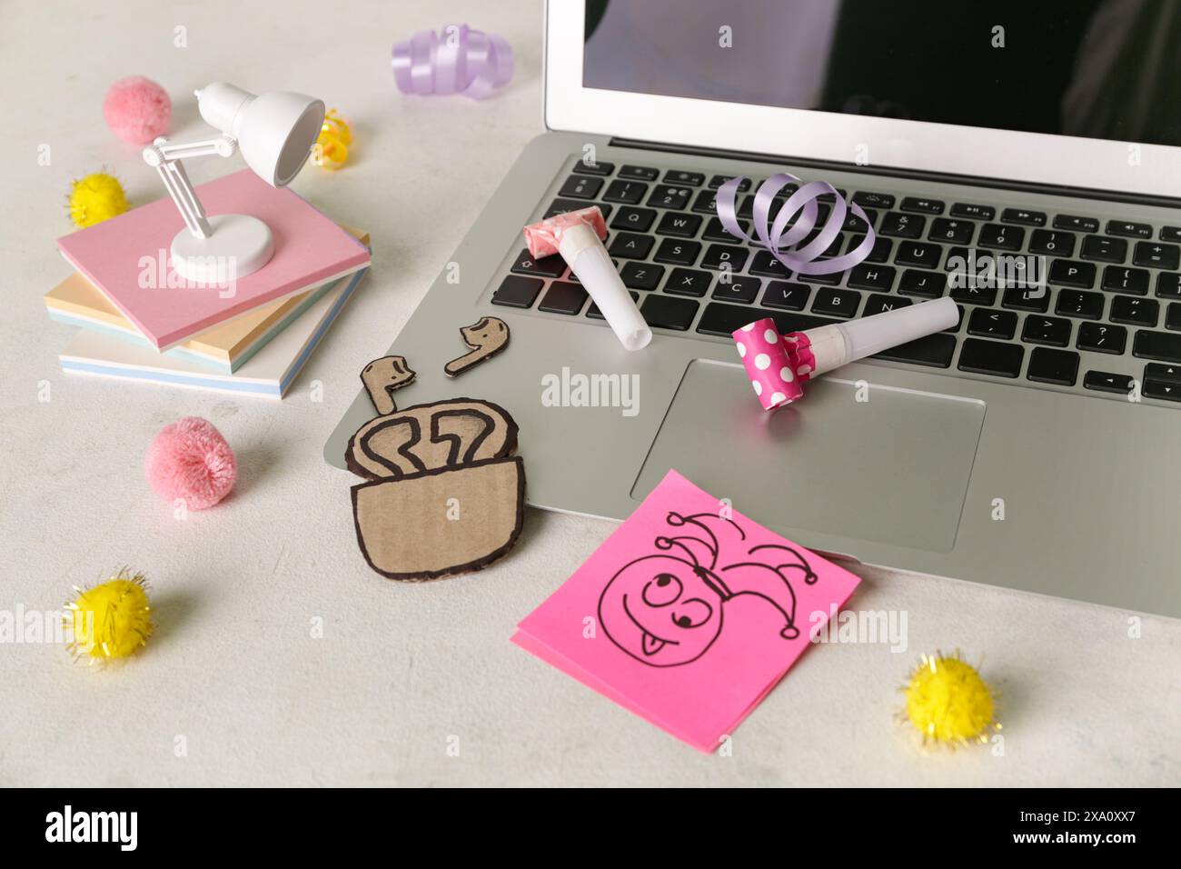 Laptop with carton earphones, sticky note and party decor on white ...